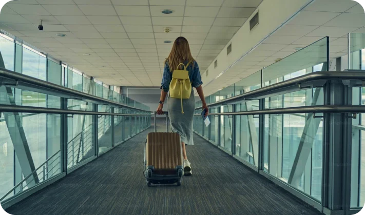 Passenger with luggage walking through airport corridor